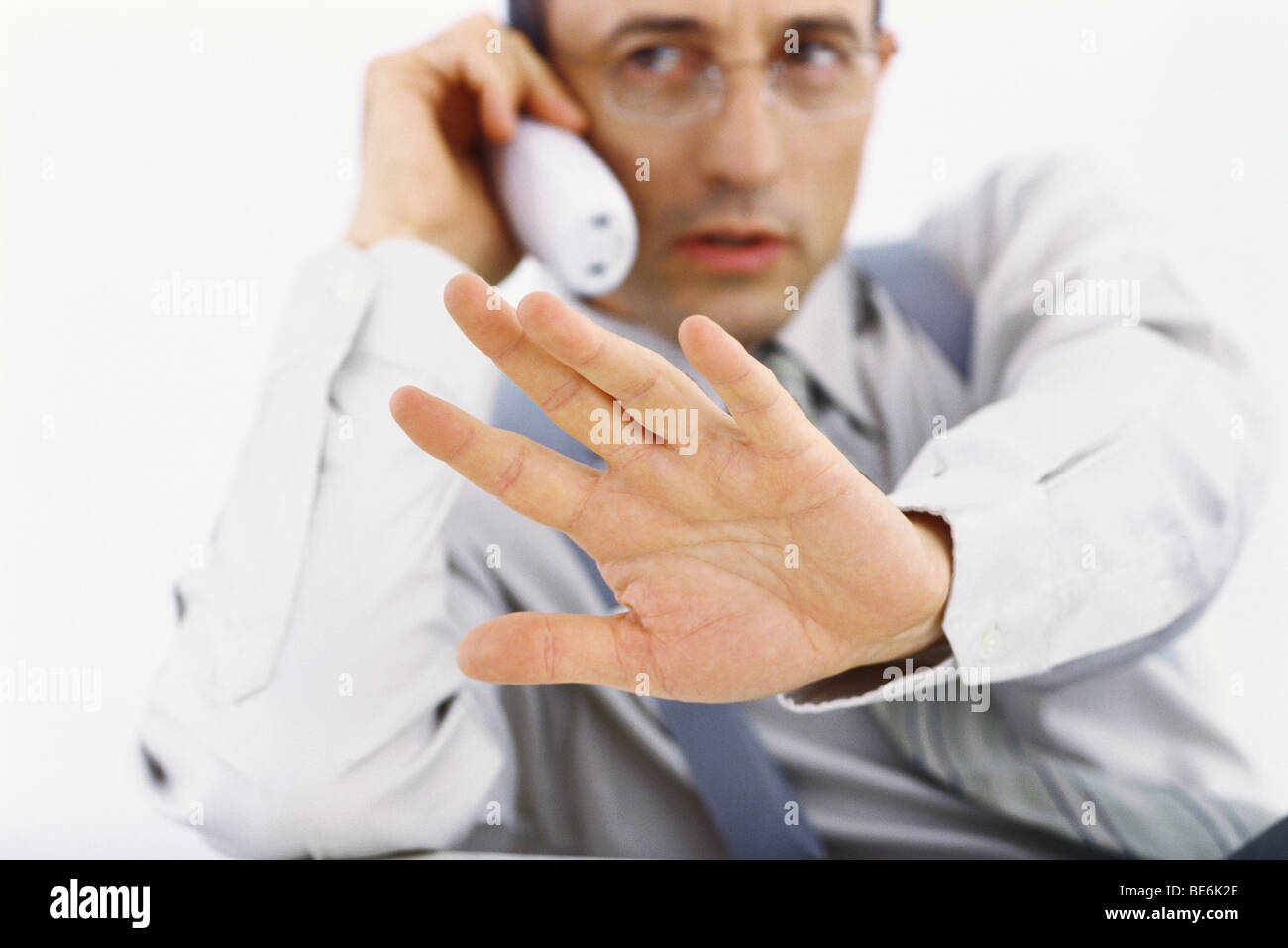 Businessman on phone call making stop gesture with hand Stock Photo - Alamy