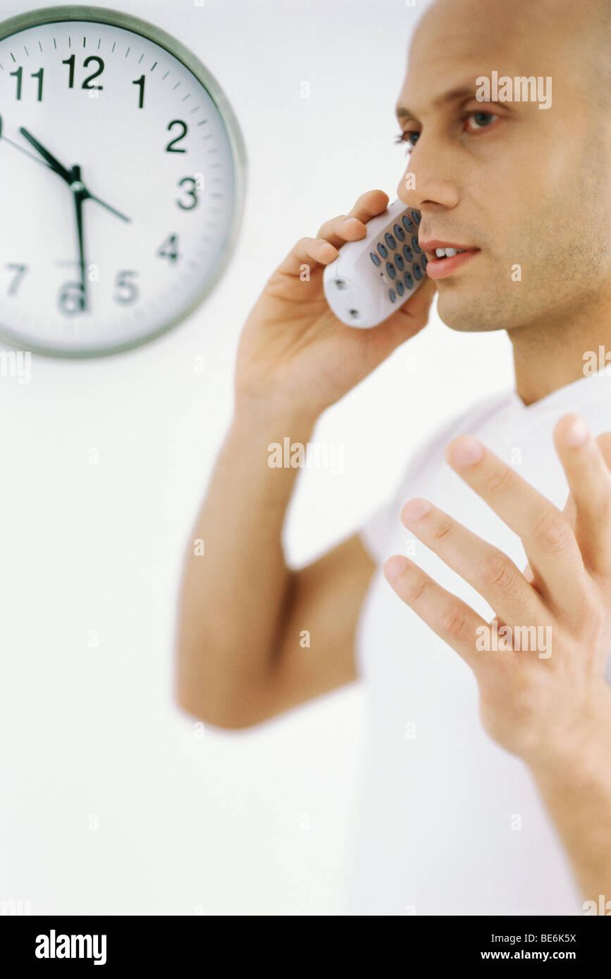 Man on phone call, clock in background Stock Photo - Alamy