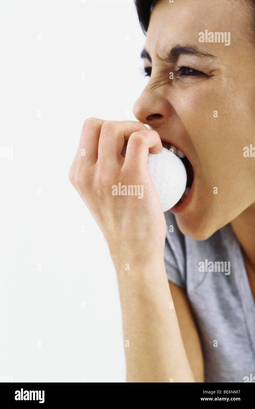 Woman biting into golf ball Stock Photo - Alamy