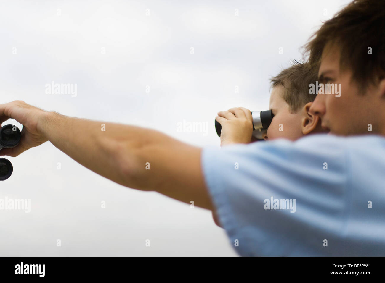 Father and son looking through binoculars, side view Stock Photo - Alamy