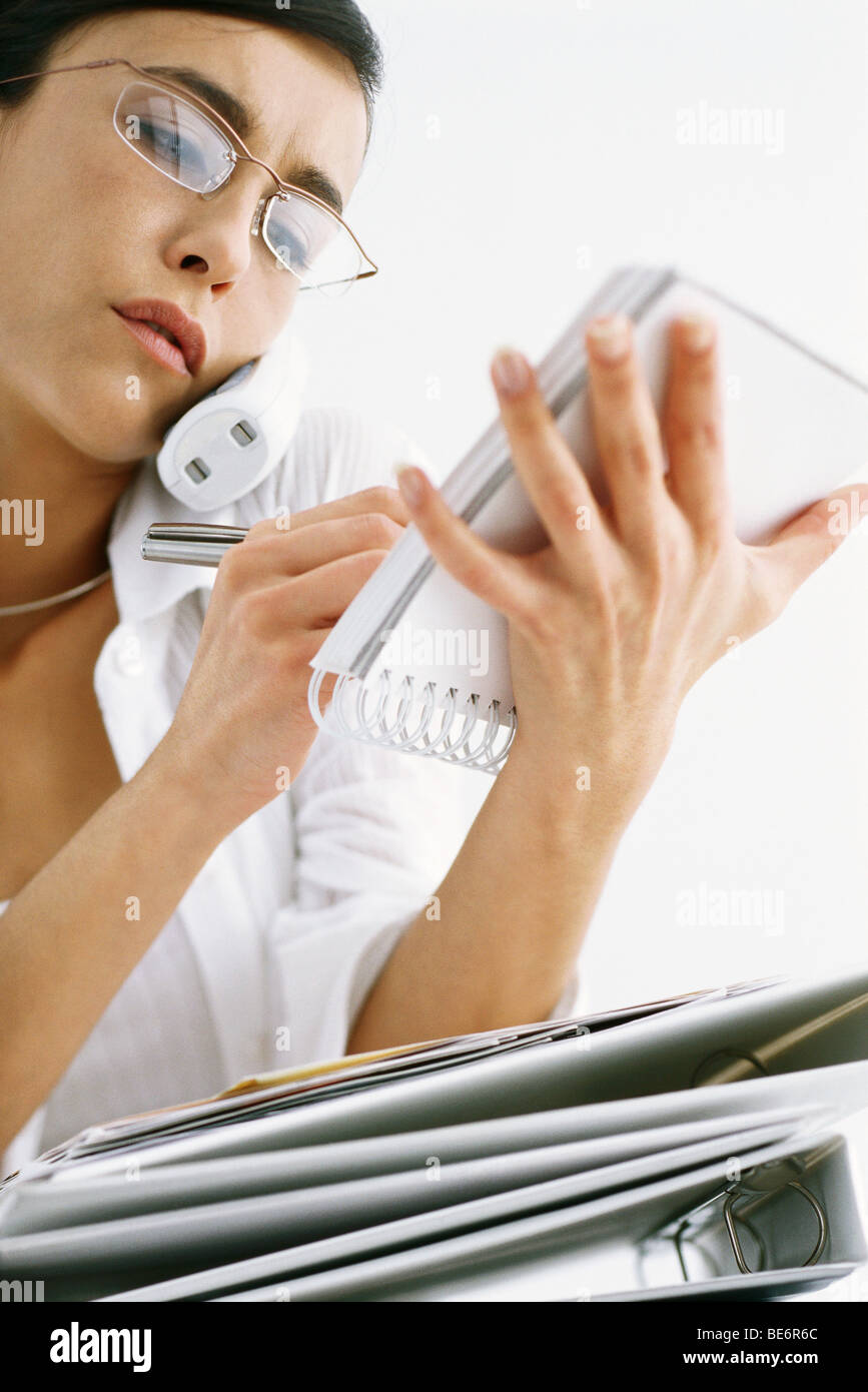 Woman on phone call writing notes in notepad Stock Photo - Alamy