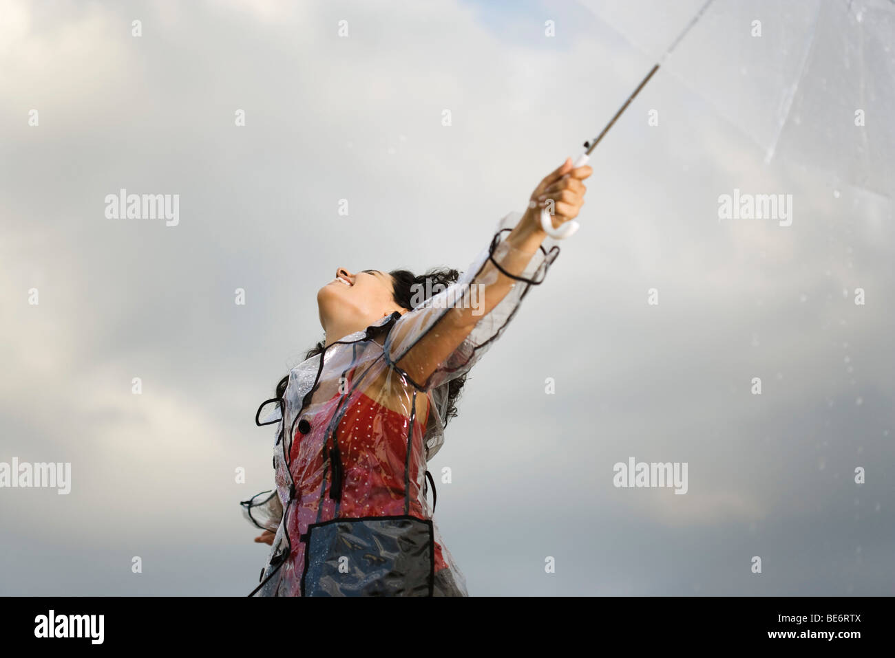 Young woman standing outdoors on rainy day, letting rain fall on her ...