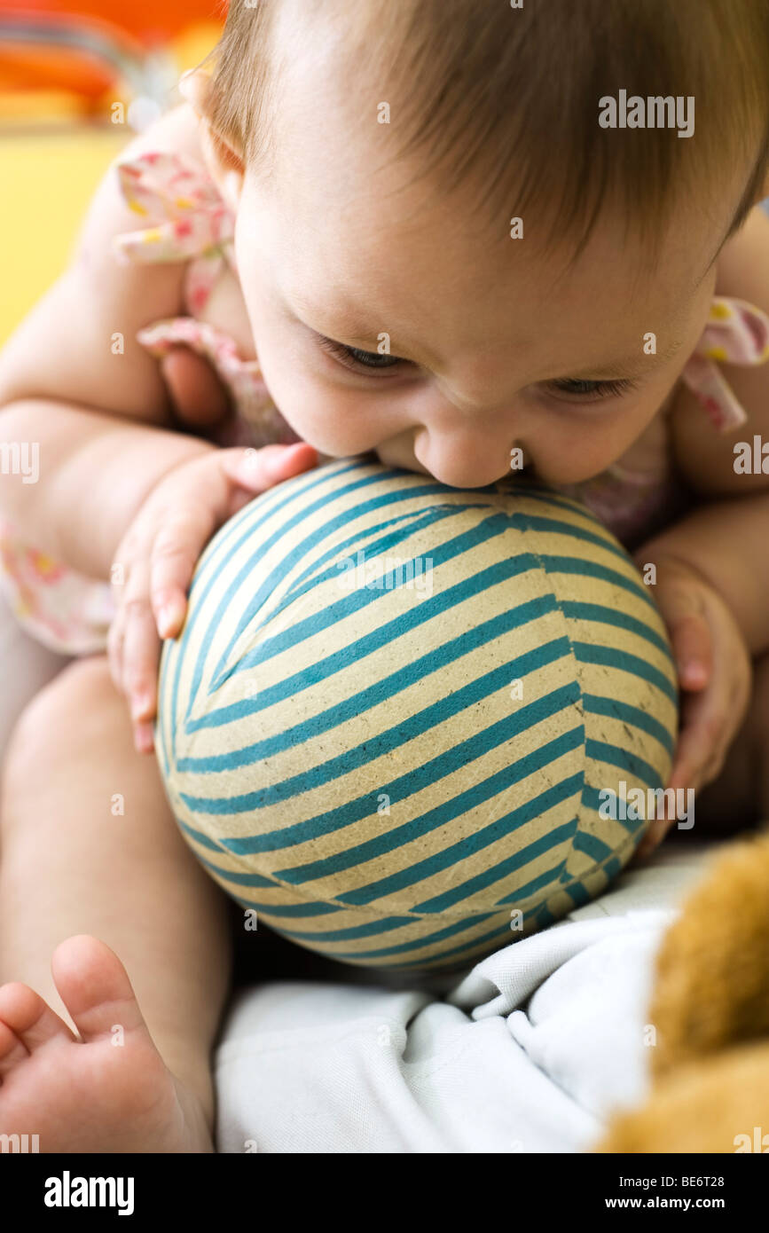 Infant chewing on striped ball Stock Photo - Alamy