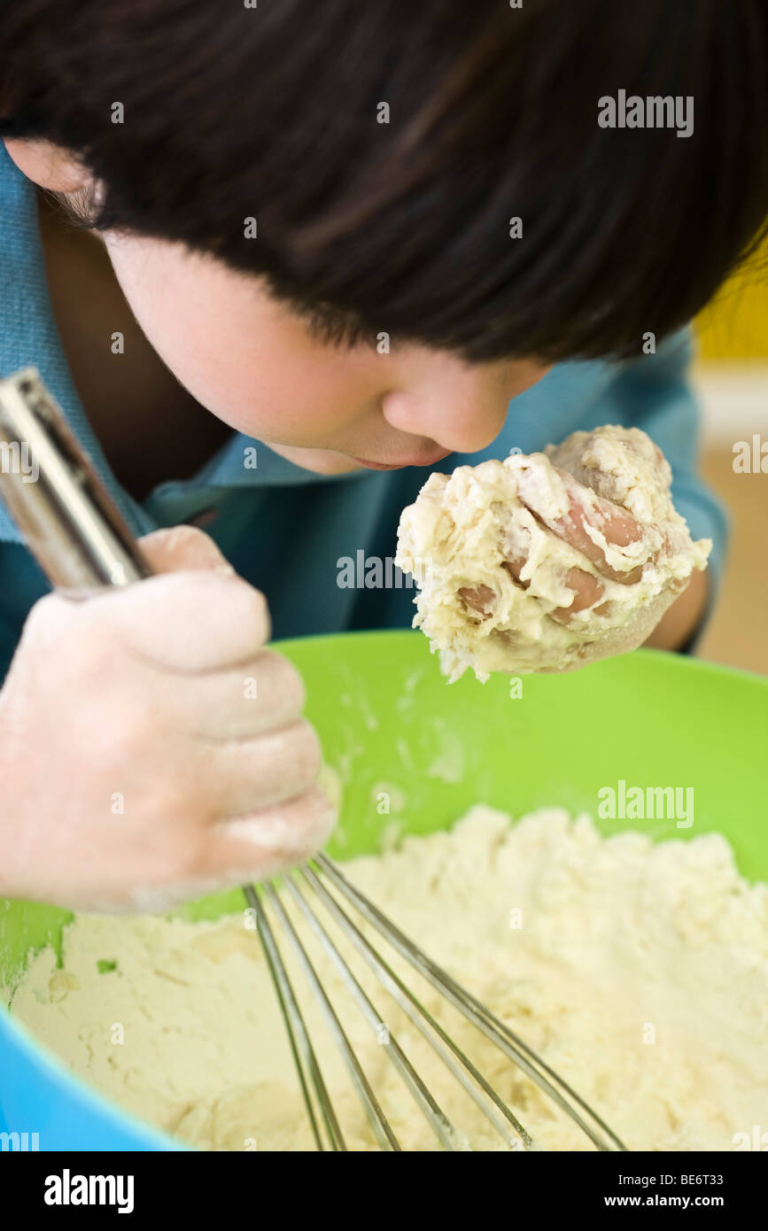 Little boy leaning over mixing bowl, smelling handful of dough Stock ...