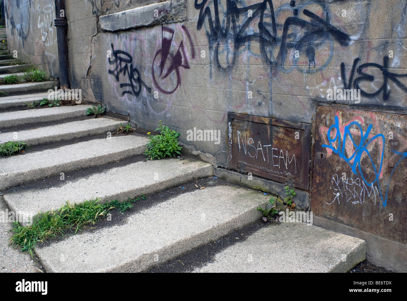 Steps with two rusty metal doors in a graffiti covered wall Stock Photo ...