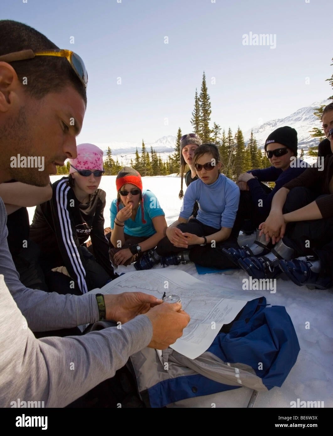 Teacher explains navigation with map and compass to a group of children ...
