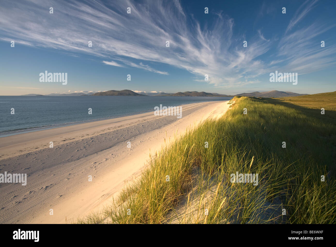 Strong summer sun lights the beach and dunes under dramatic streamers ...