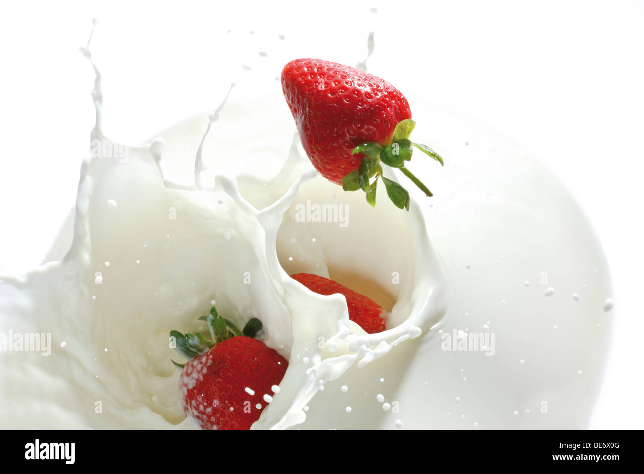 Strawberries falling into milk Stock Photo - Alamy