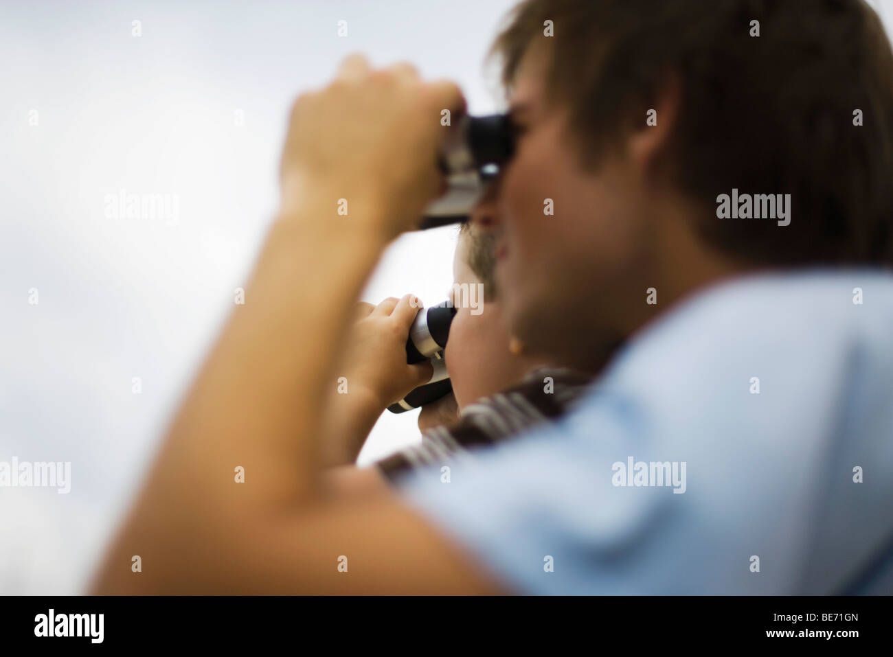 Father and son looking through binoculars, side view Stock Photo - Alamy