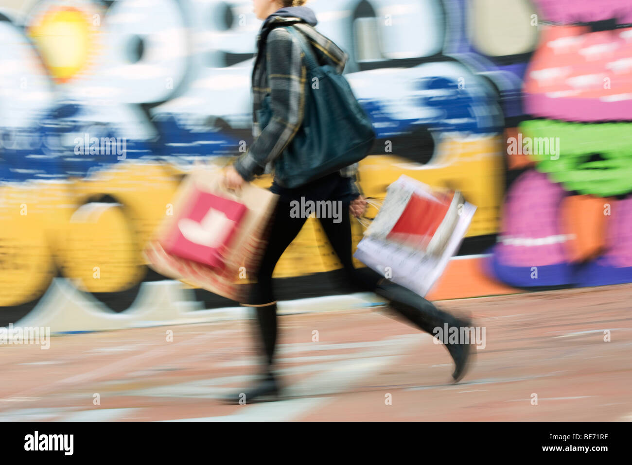 Pedestrian carrying shopping bags on sidewalk, blurred Stock Photo - Alamy