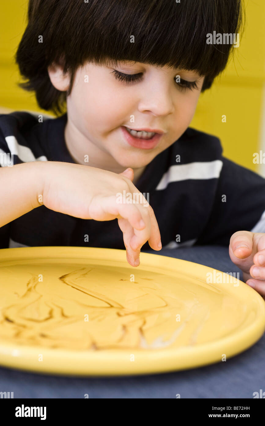 Little boy drawing on plate with finger Stock Photo - Alamy