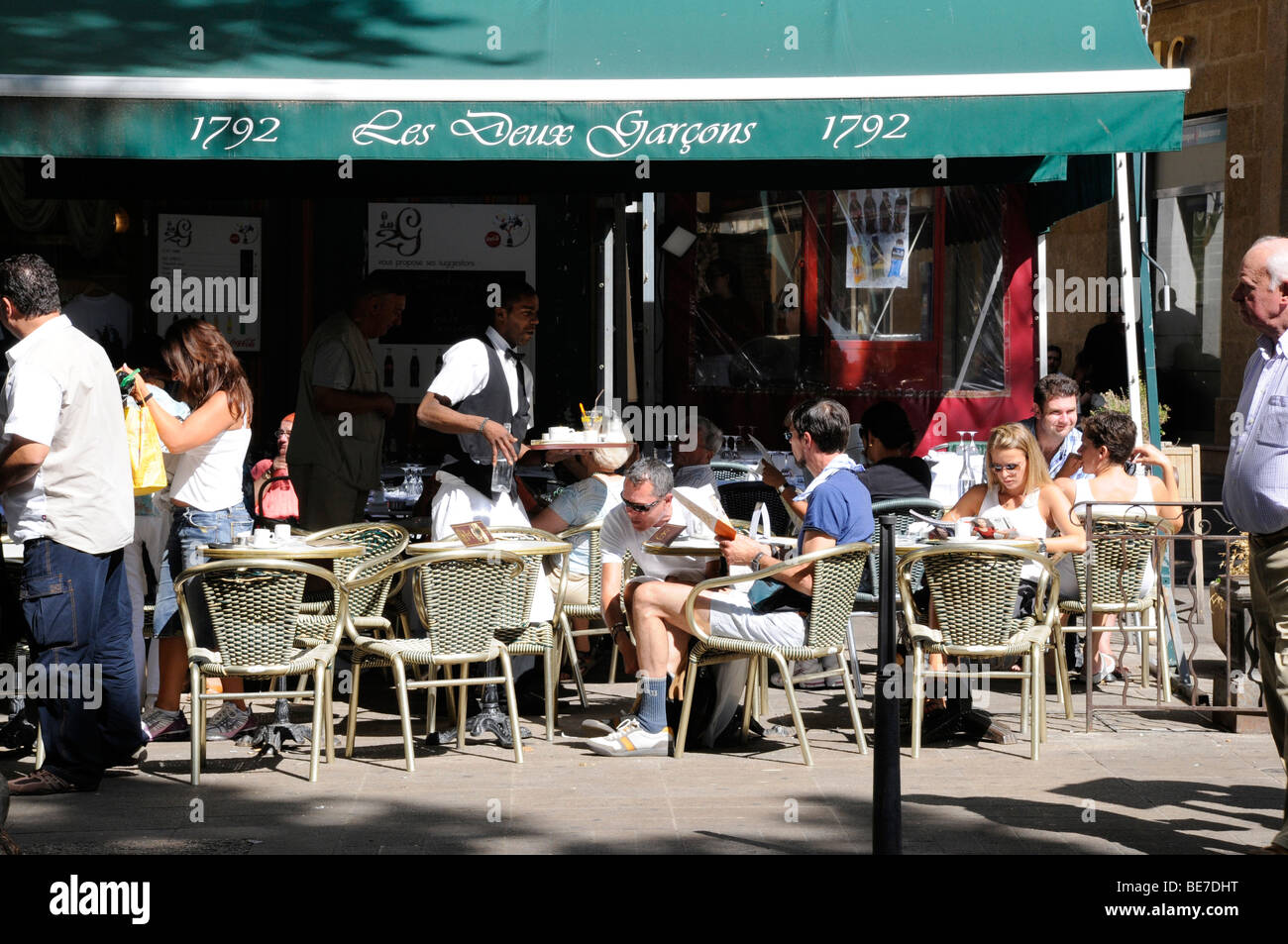 Waiter brings drinks in a busy French cafe on the Cours Mirabeau, Aix ...