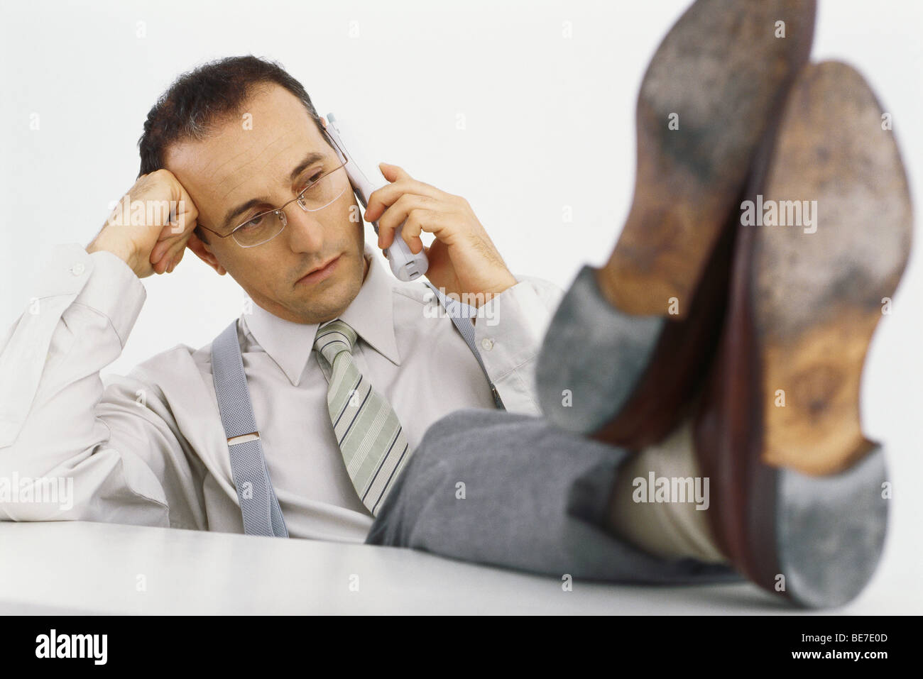 Businessman on phone call with feet up on desk Stock Photo - Alamy