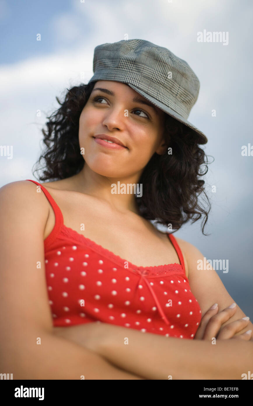 Young woman wearing cap turned to side, arms folded, portrait Stock ...