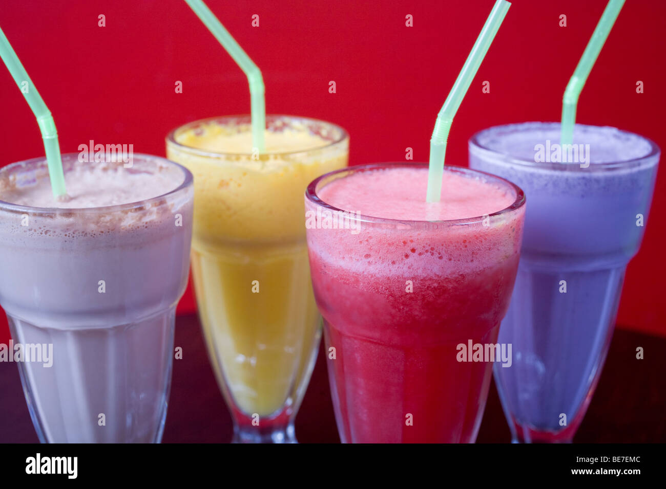 Four cool milkshakes against a brightly coloured wall. Flavours are ...