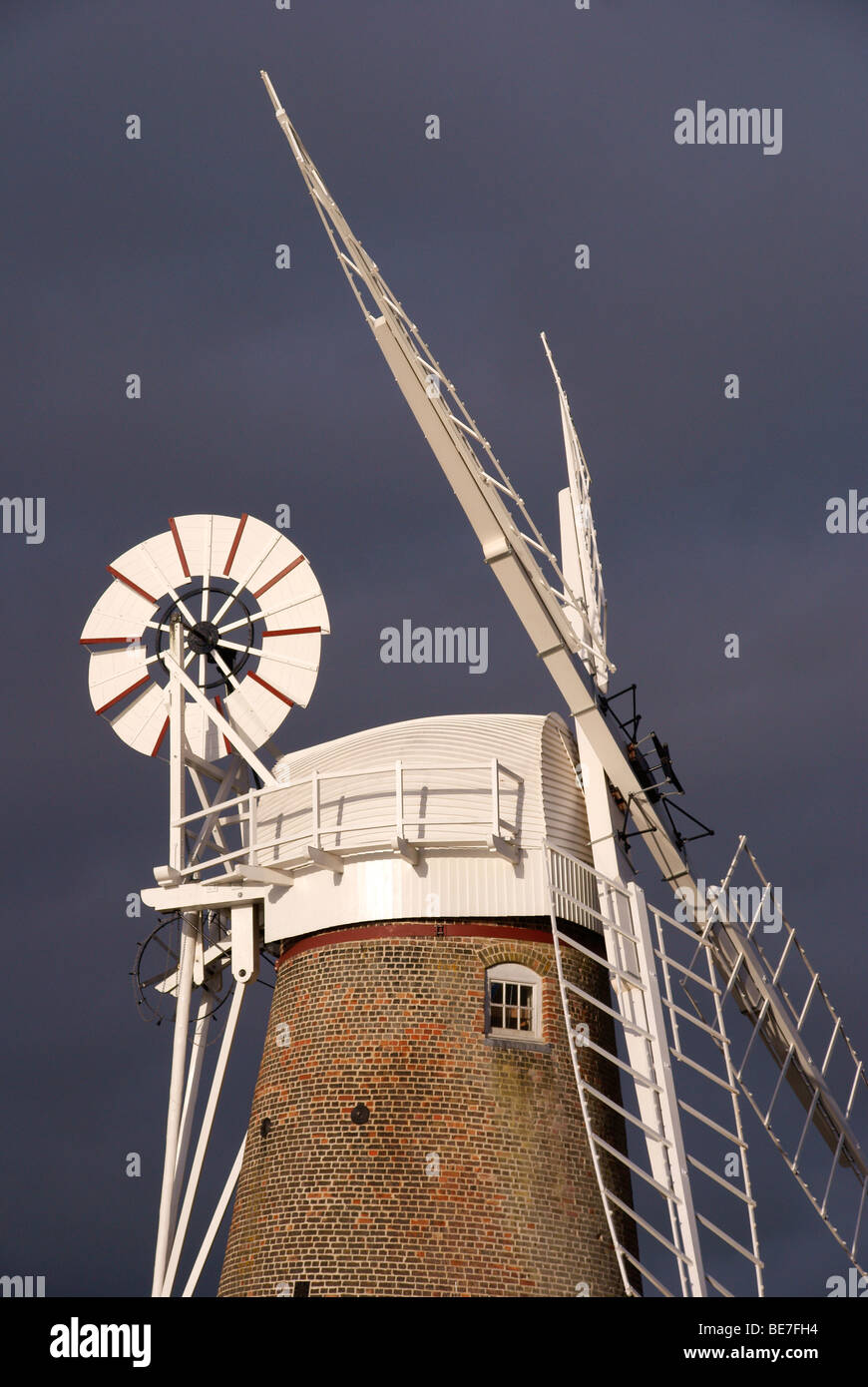 Morning sunlight catches Hardley drainage mill against a stormy dark ...