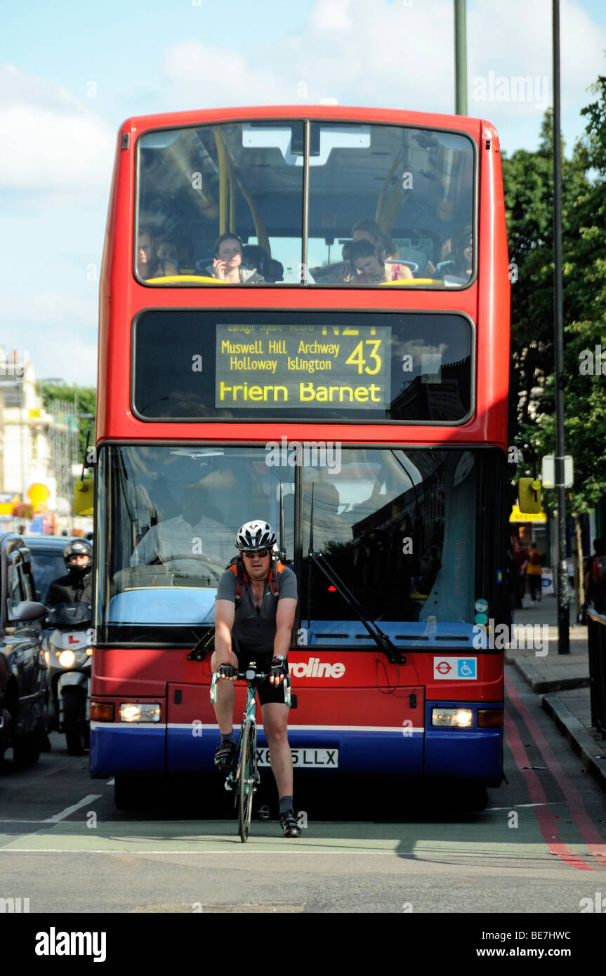 Male cyclist wearing helmet in front of bus Holloway Road Islington ...