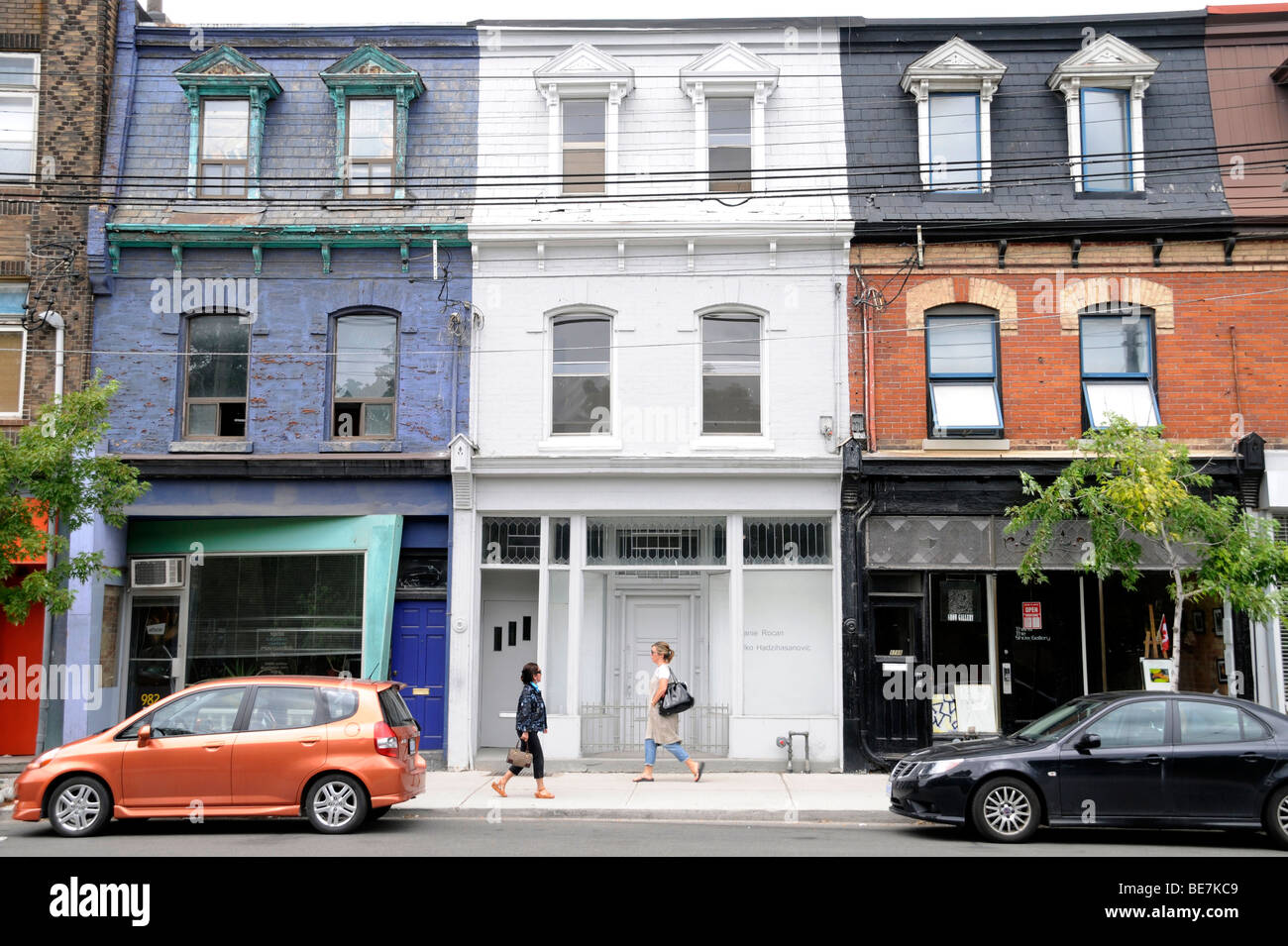Pedestrians walking by storefront residential buildings along the ...