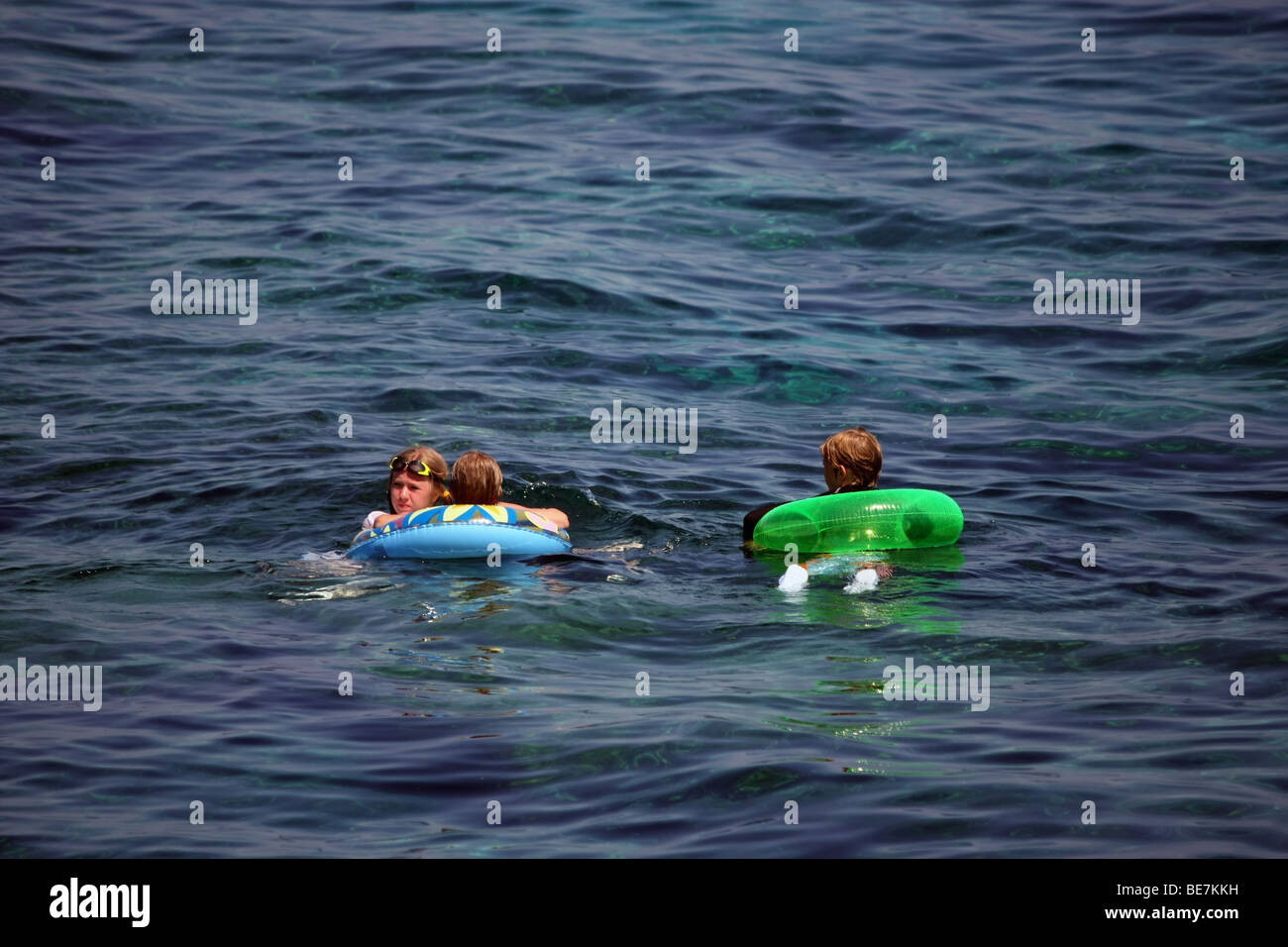 Children floating on inflatable rings in the sea at Fig Tree Bay ...