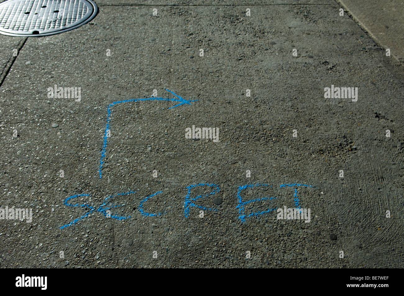 The word secret and an arrow written in blue chalk on a sidewalk Stock ...