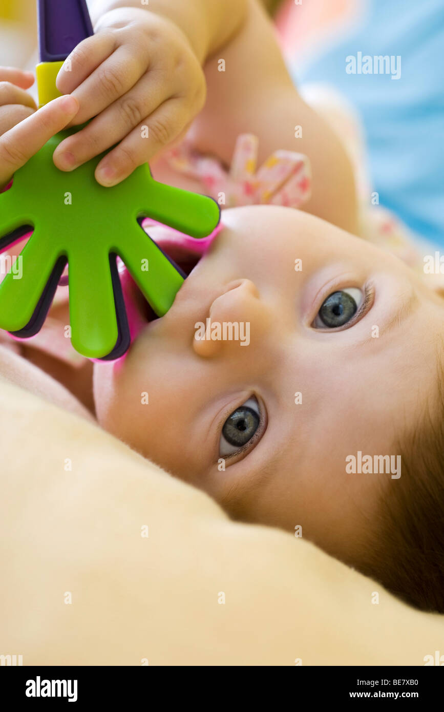 Infant girl chewing on plastic toy, looking at camera Stock Photo - Alamy