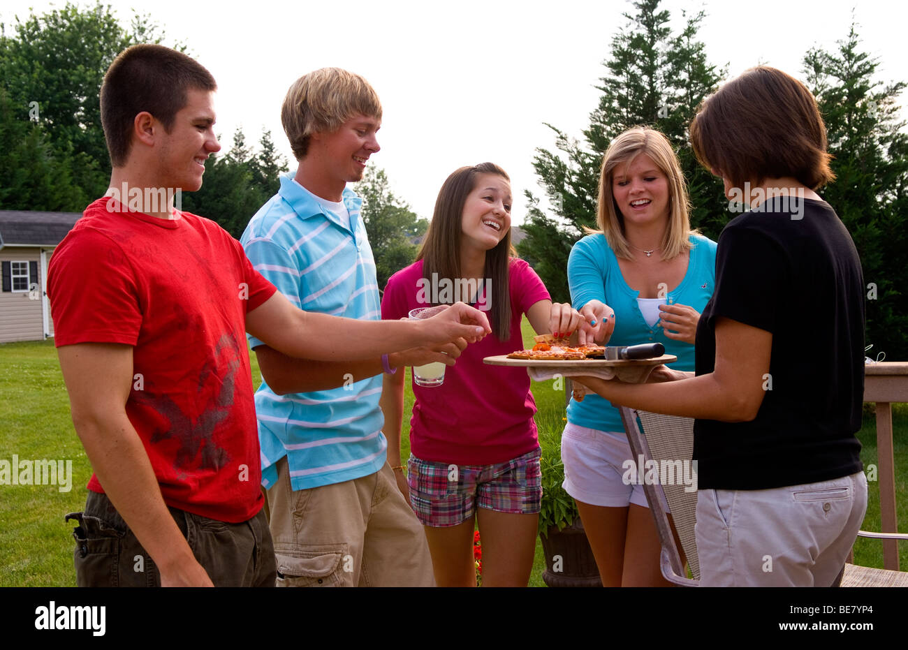 Modern teenagers hanging out at home as friends having pizza and ...