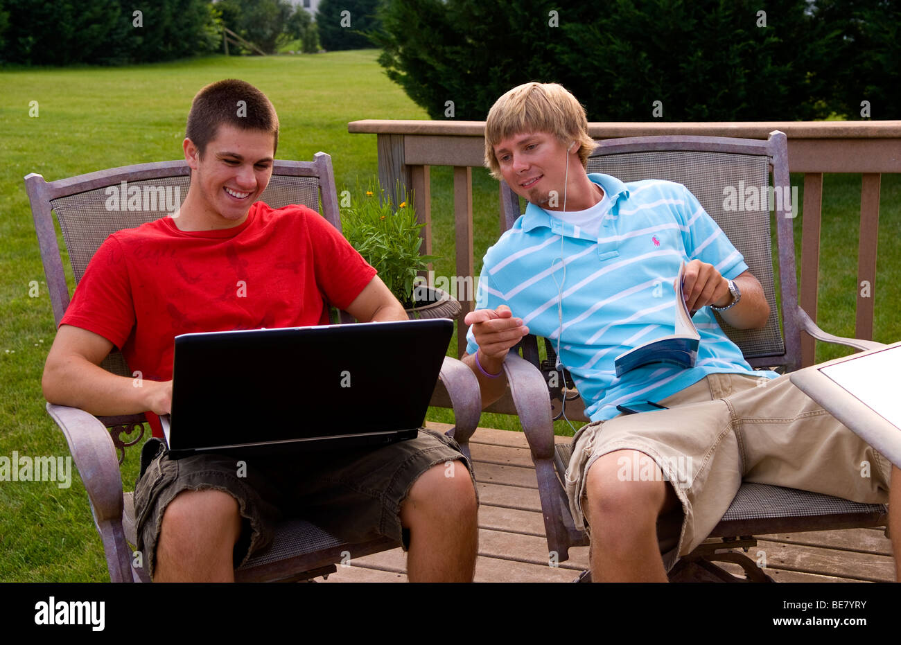 Modern teenager reading outside in yard at home and other looking at ...