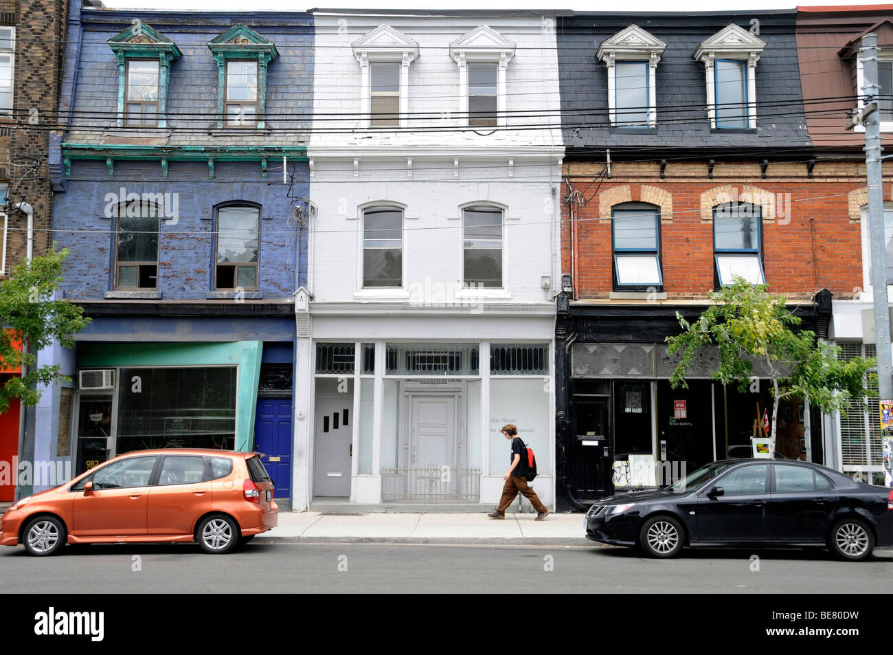 A pedestrian walking by storefront residential buildings along the ...