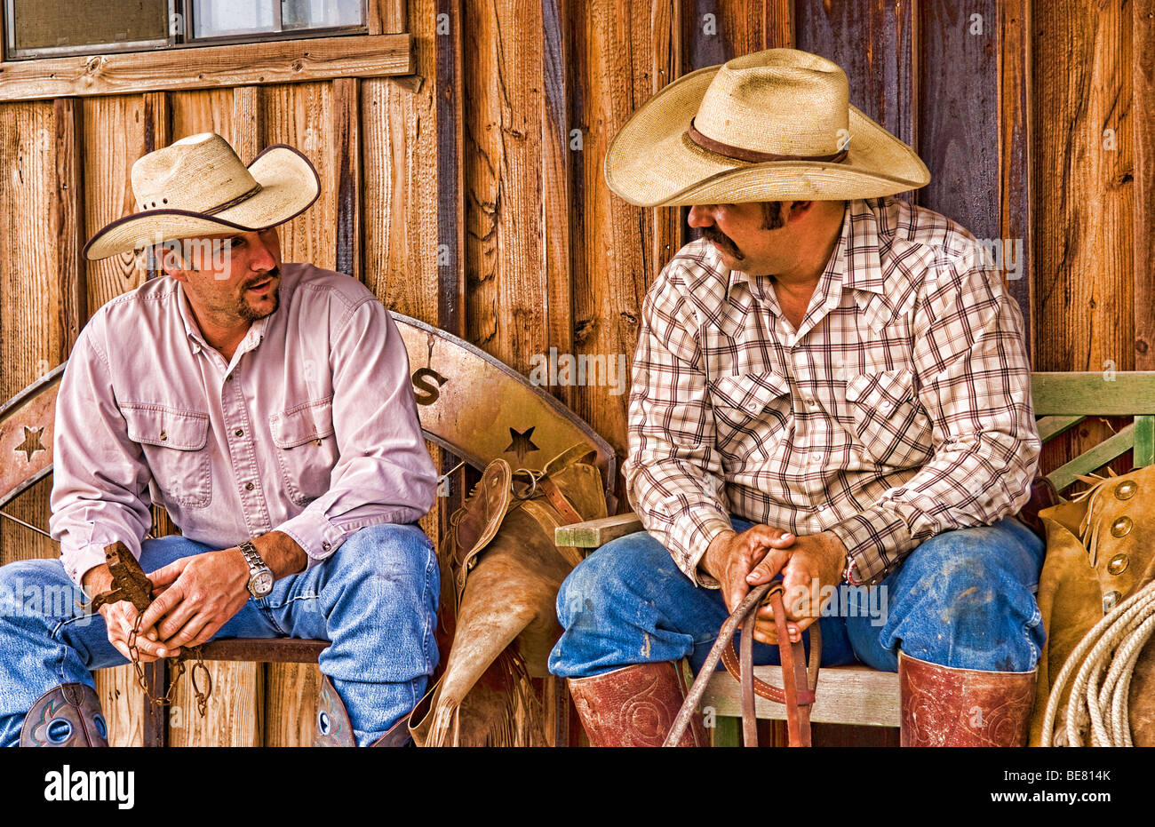 The cowboy life in the USA West as cowboys relax and talk on old porch ...