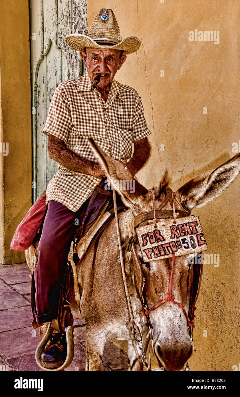 Old man riding donkey for tourists in the old colonial city of Trinidad ...