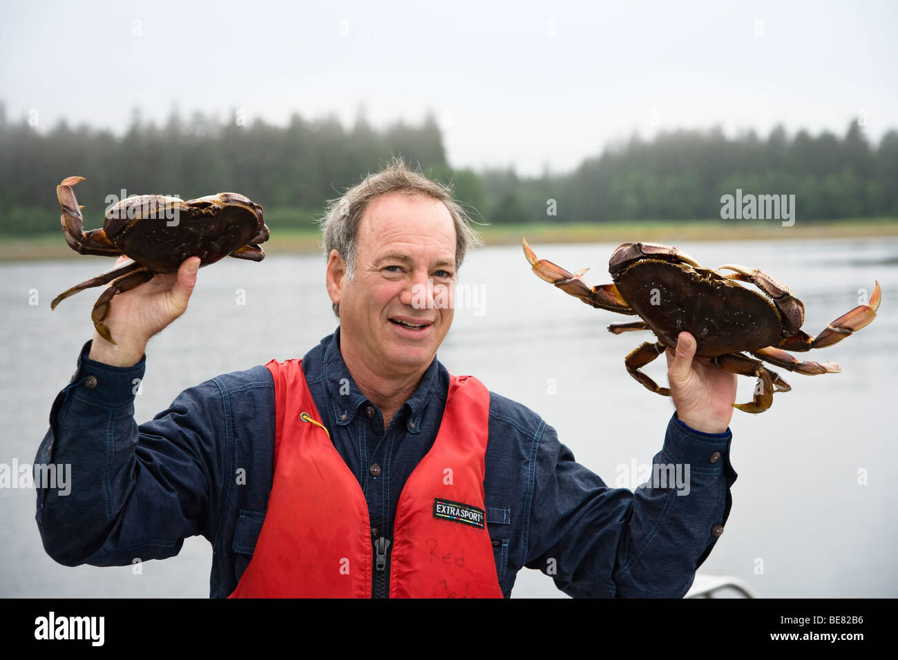 Mature man showing two crabs, Inside Passage, Southeast Alaska, USA ...