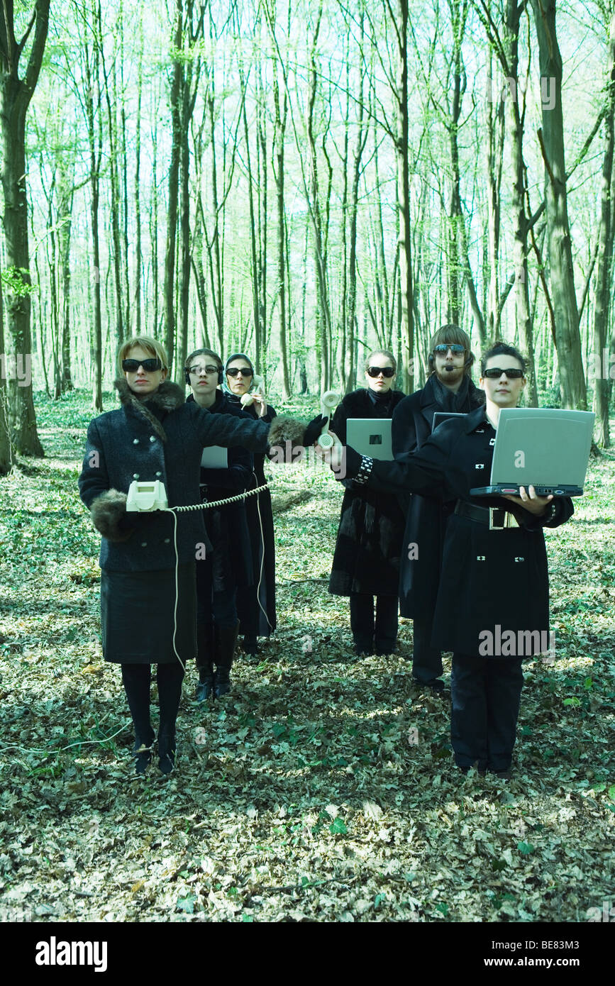 People dressed all in black lined up in woods, holding laptop computers ...