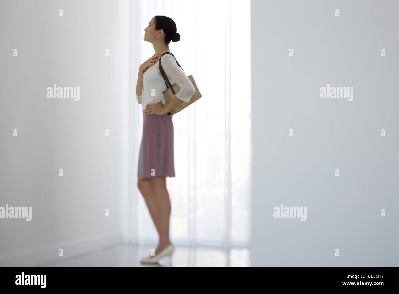 Woman standing beside window, looking up, side view Stock Photo - Alamy