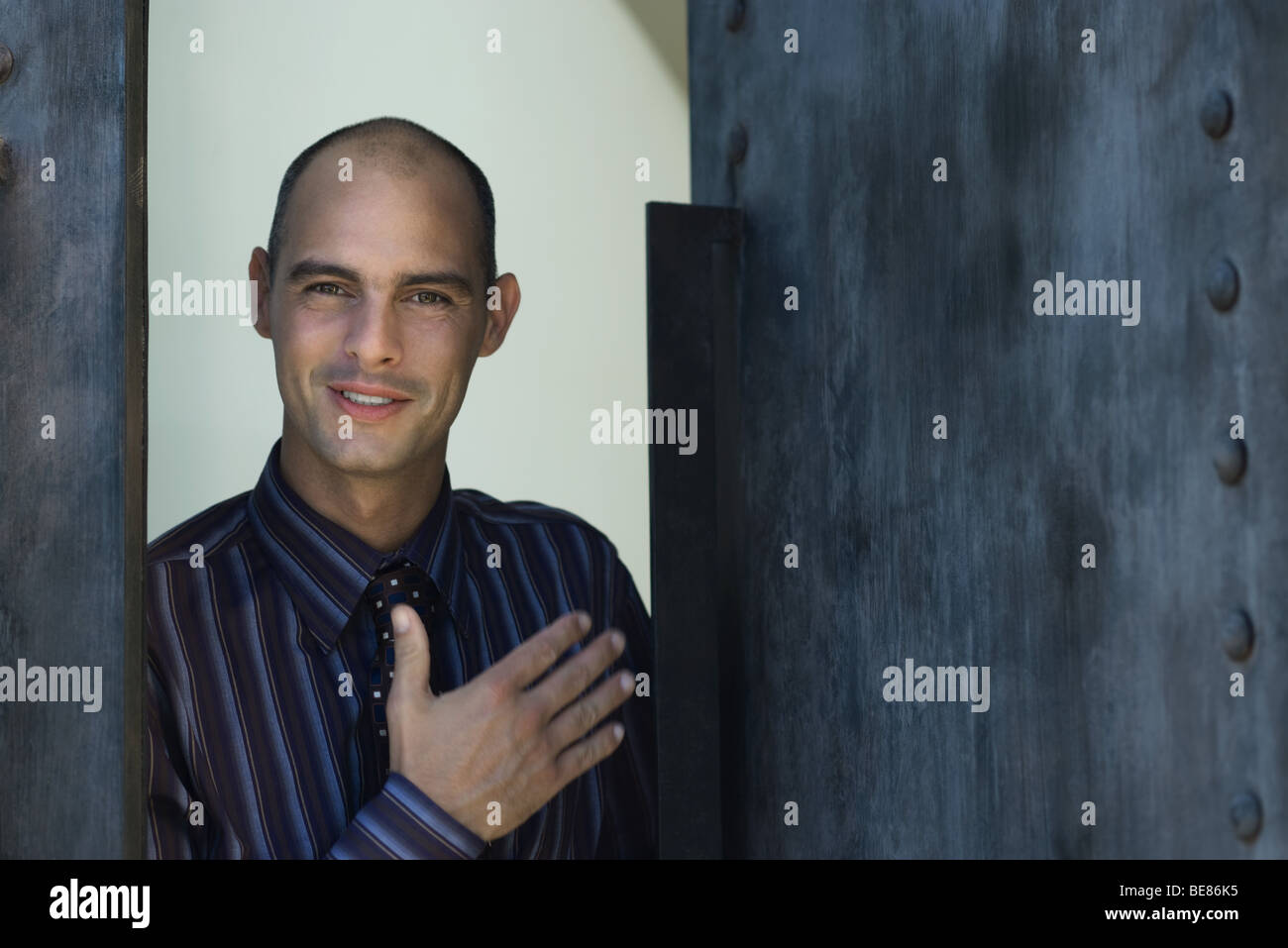 Man opening door, smiling, hand on chest Stock Photo - Alamy