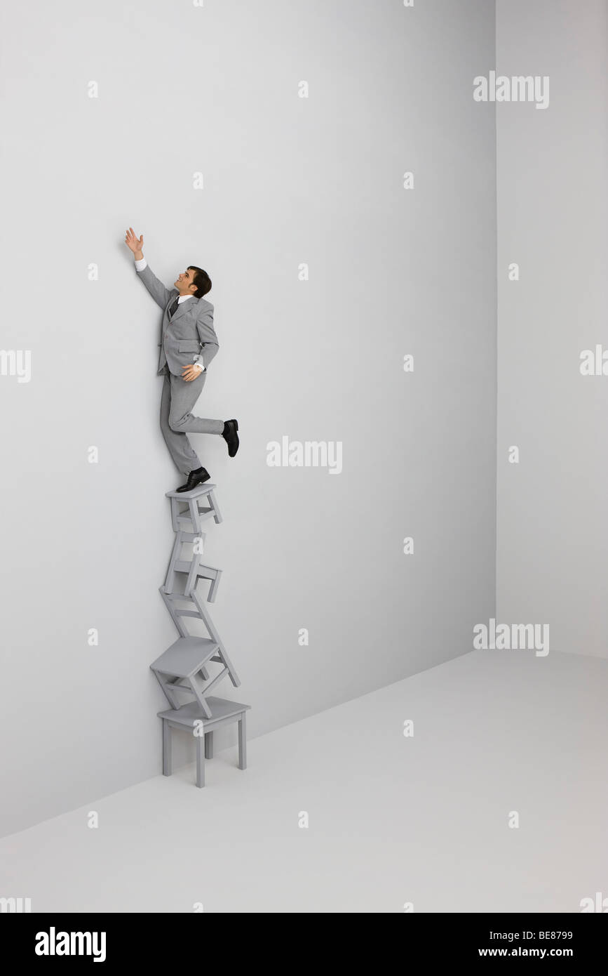 Businessman standing on top of stack of chairs Stock Photo - Alamy