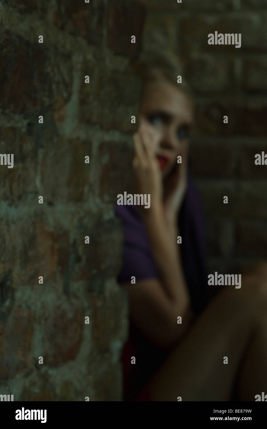 Female hiding in corner, holding head, peering at camera Stock Photo ...