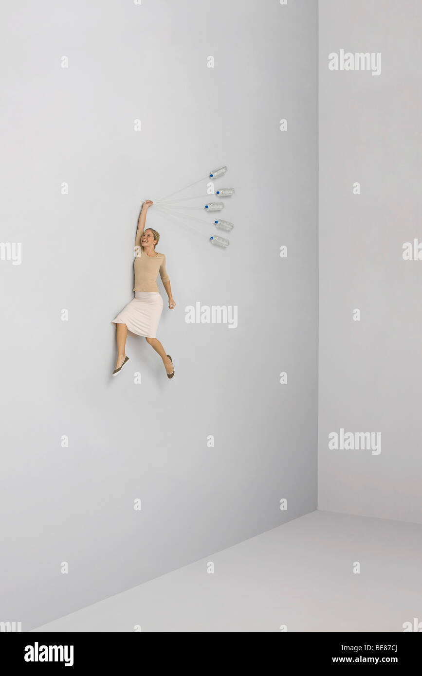 Woman held aloft by bunch of water bottles Stock Photo - Alamy