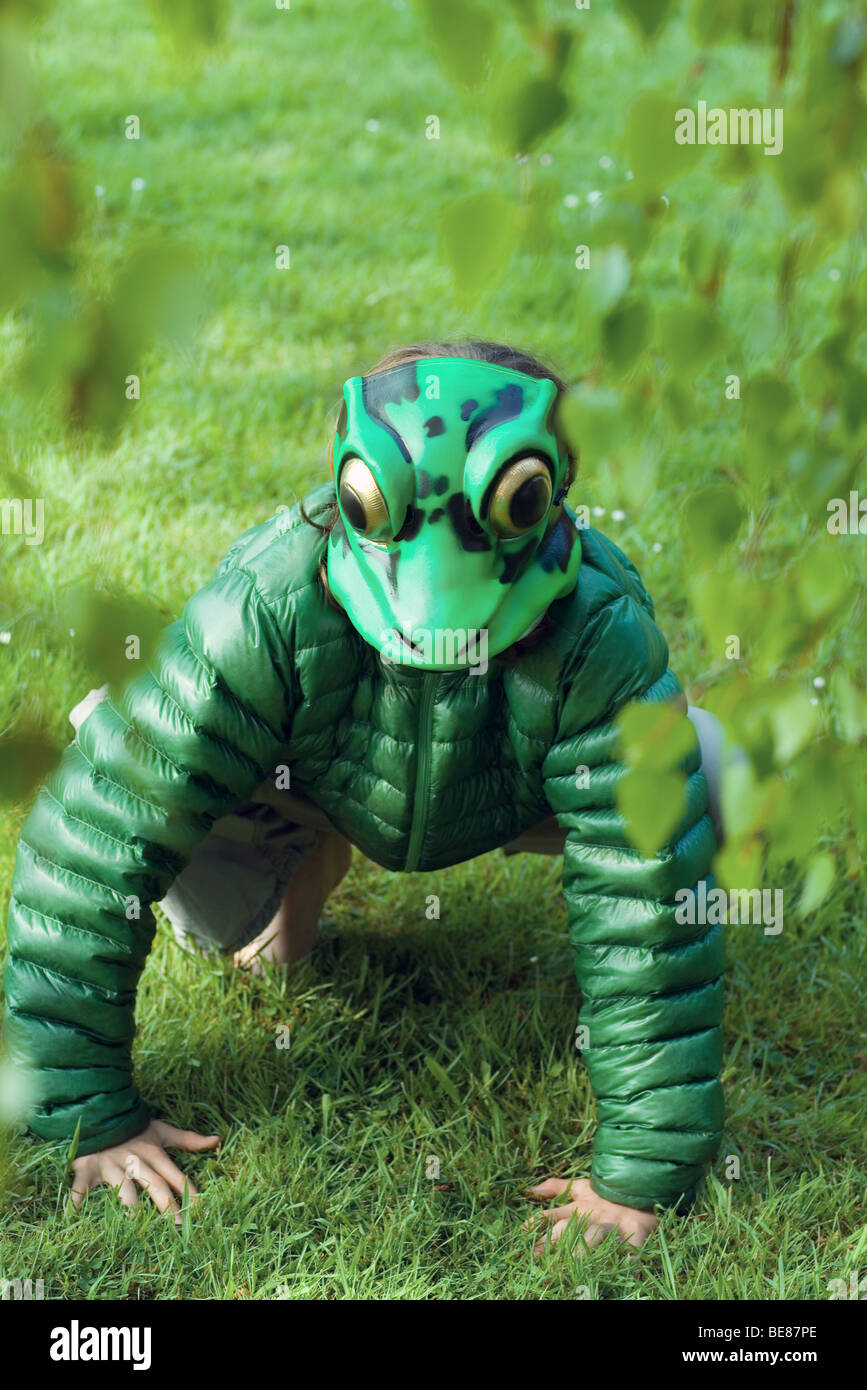 Person wearing frog mask, crouching on lawn Stock Photo - Alamy
