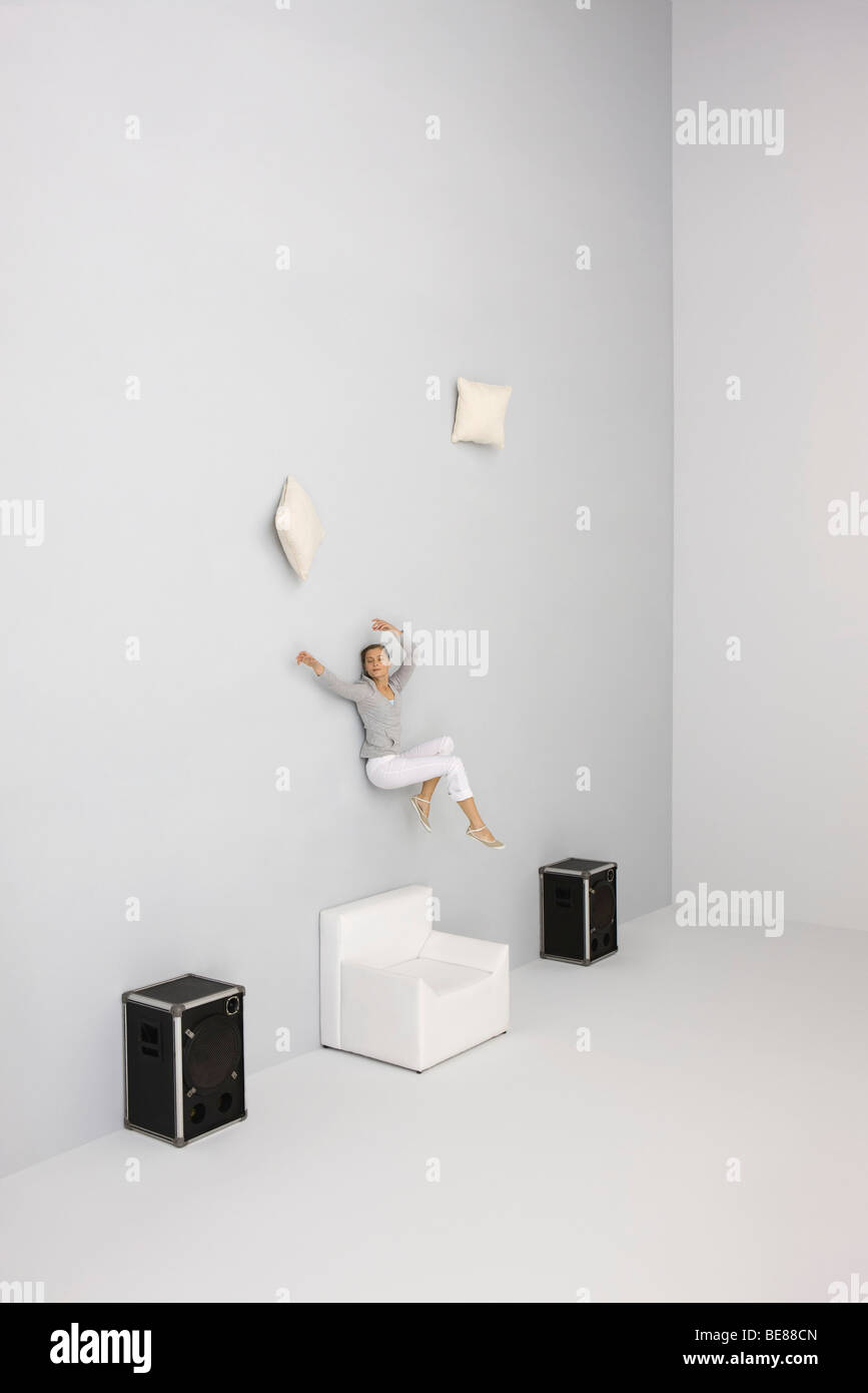 Woman with listening to music through speakers, floating in midair ...