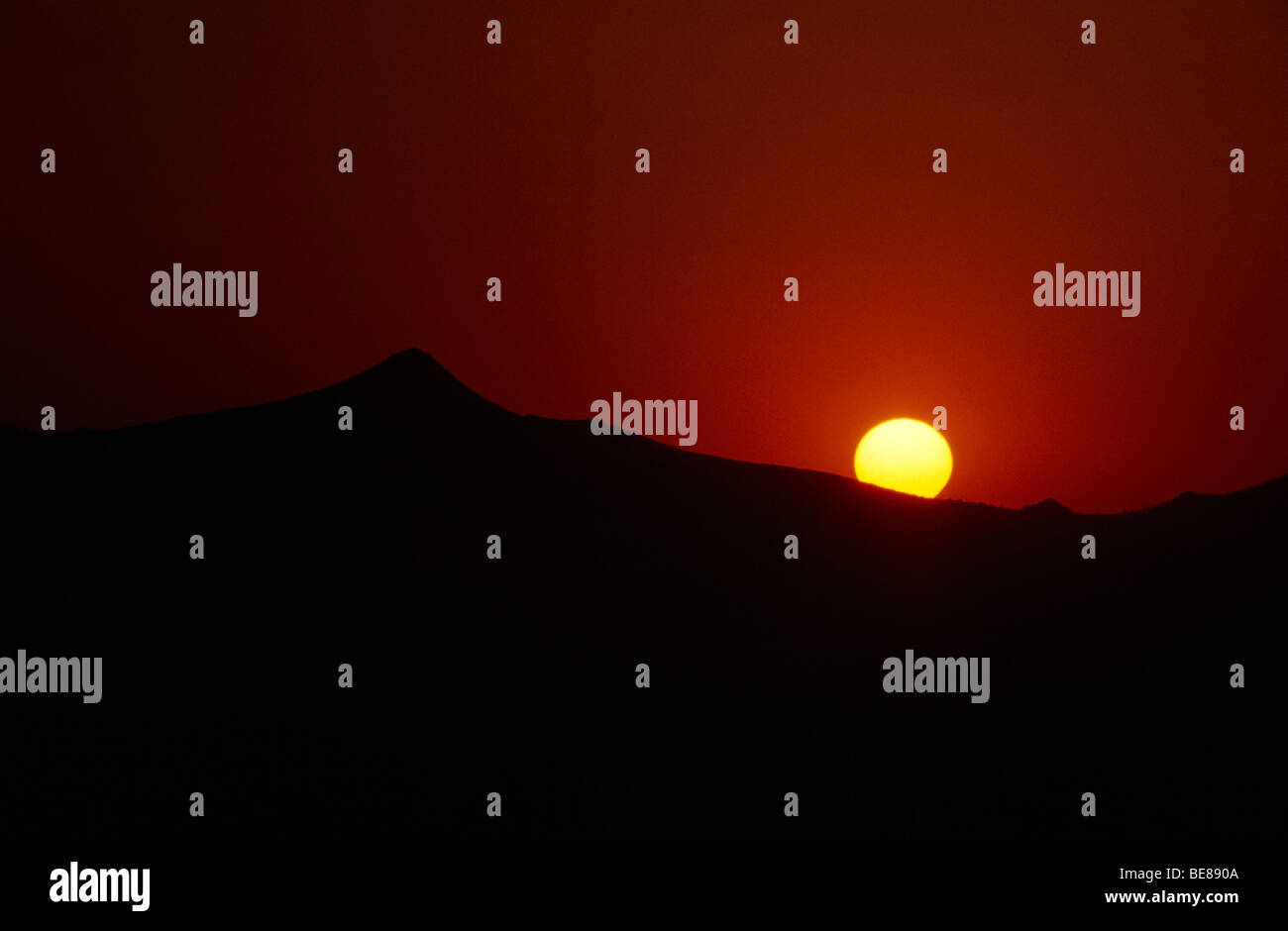 WEATHER Climate Sunset Red sun setting over hills Stock Photo - Alamy
