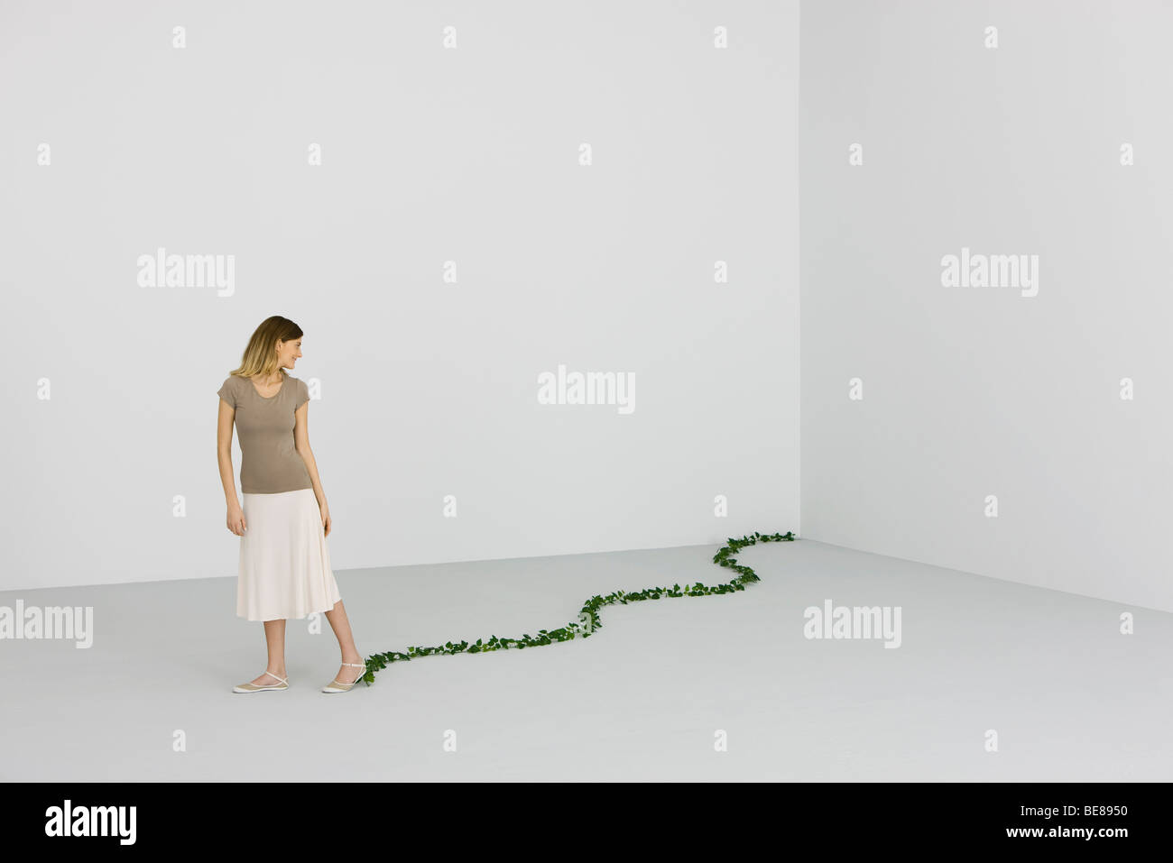 Woman walking, looking over shoulder at vine trailing behind her Stock ...