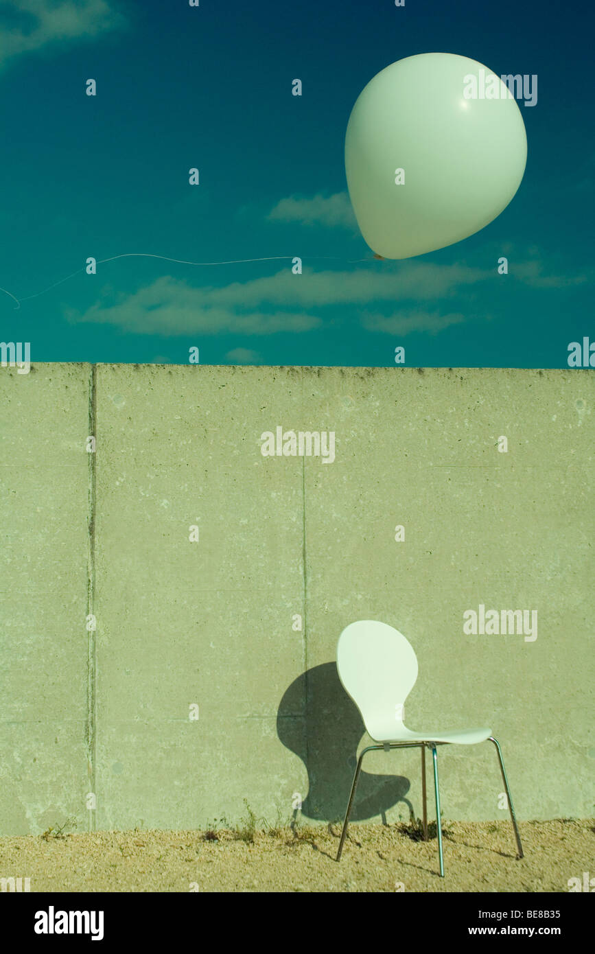 Chair set near concrete wall, balloon floating overhead Stock Photo - Alamy