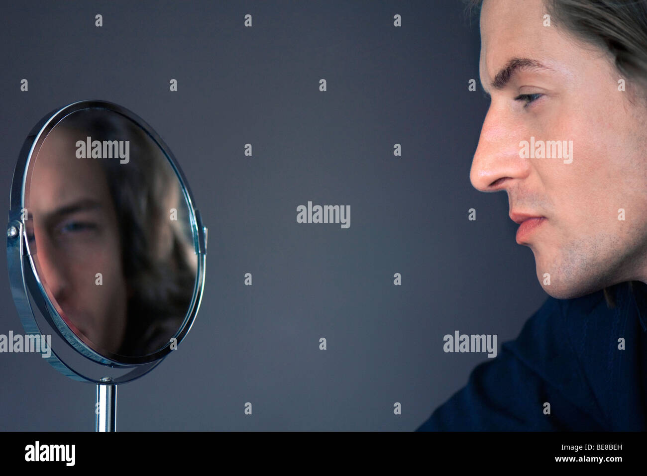 Man looking at self in cosmetic mirror Stock Photo - Alamy