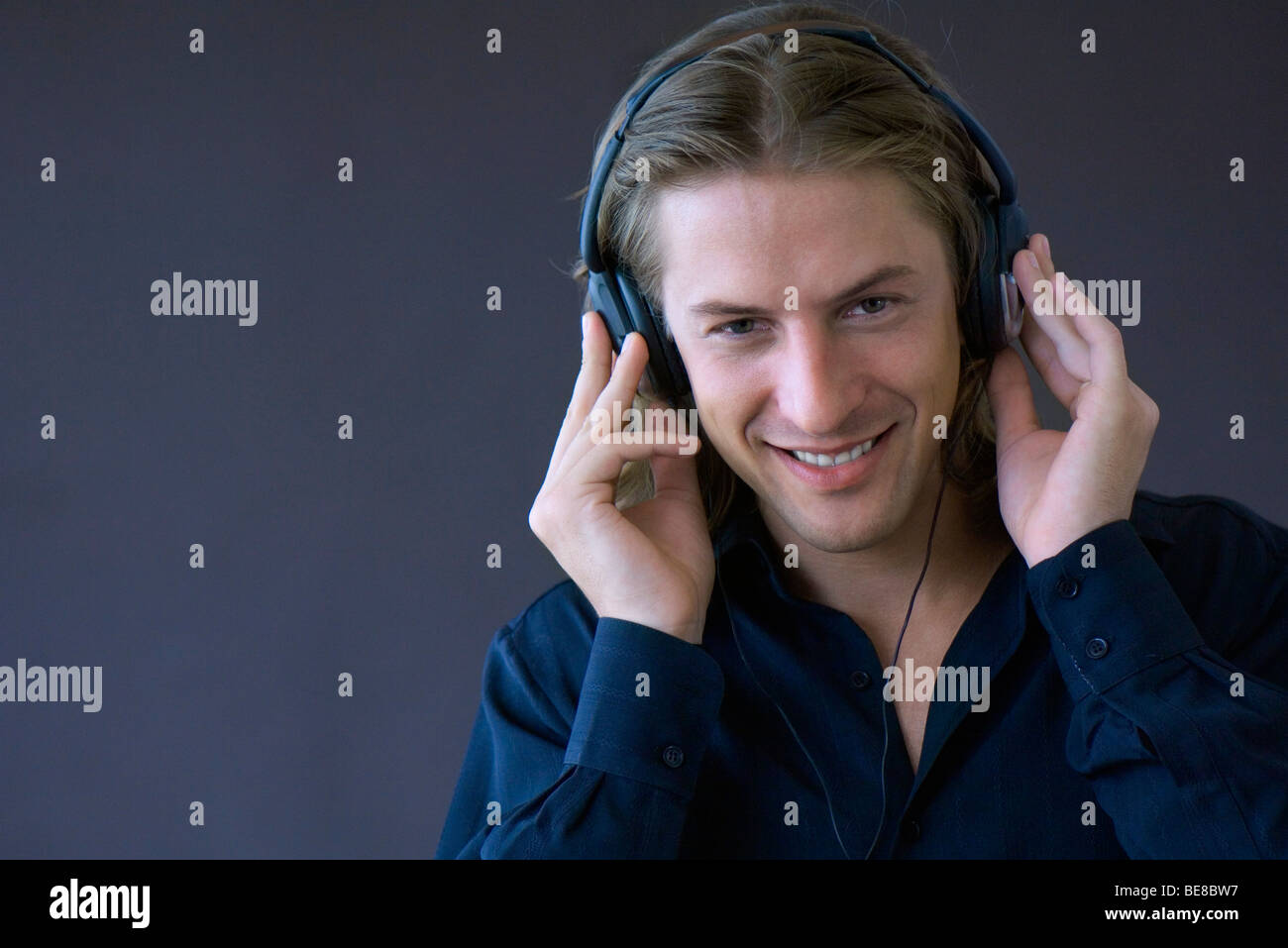 Man smiling listening to music through headphones Stock Photo - Alamy