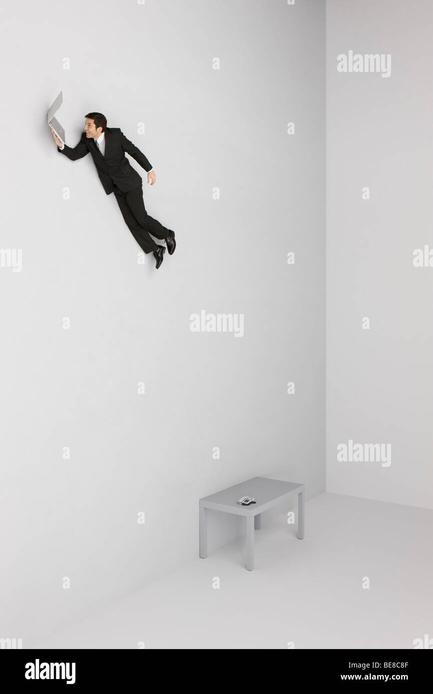 Businessman holding laptop computer flying away from desk below Stock ...