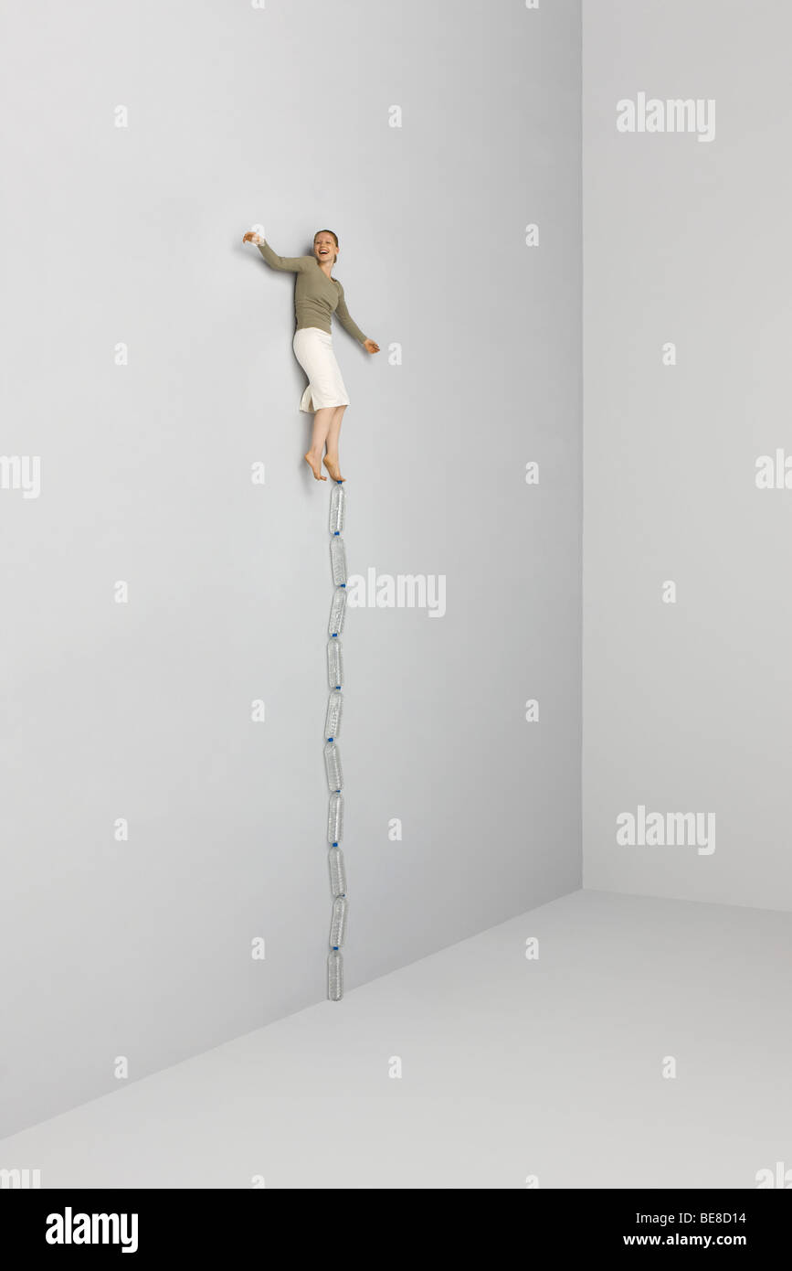 Woman balancing on one foot on top of stack of water bottles Stock ...