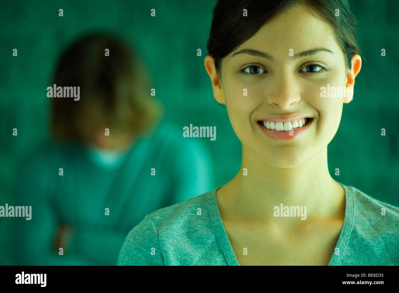 Woman smiling, man in background with head lowered Stock Photo - Alamy