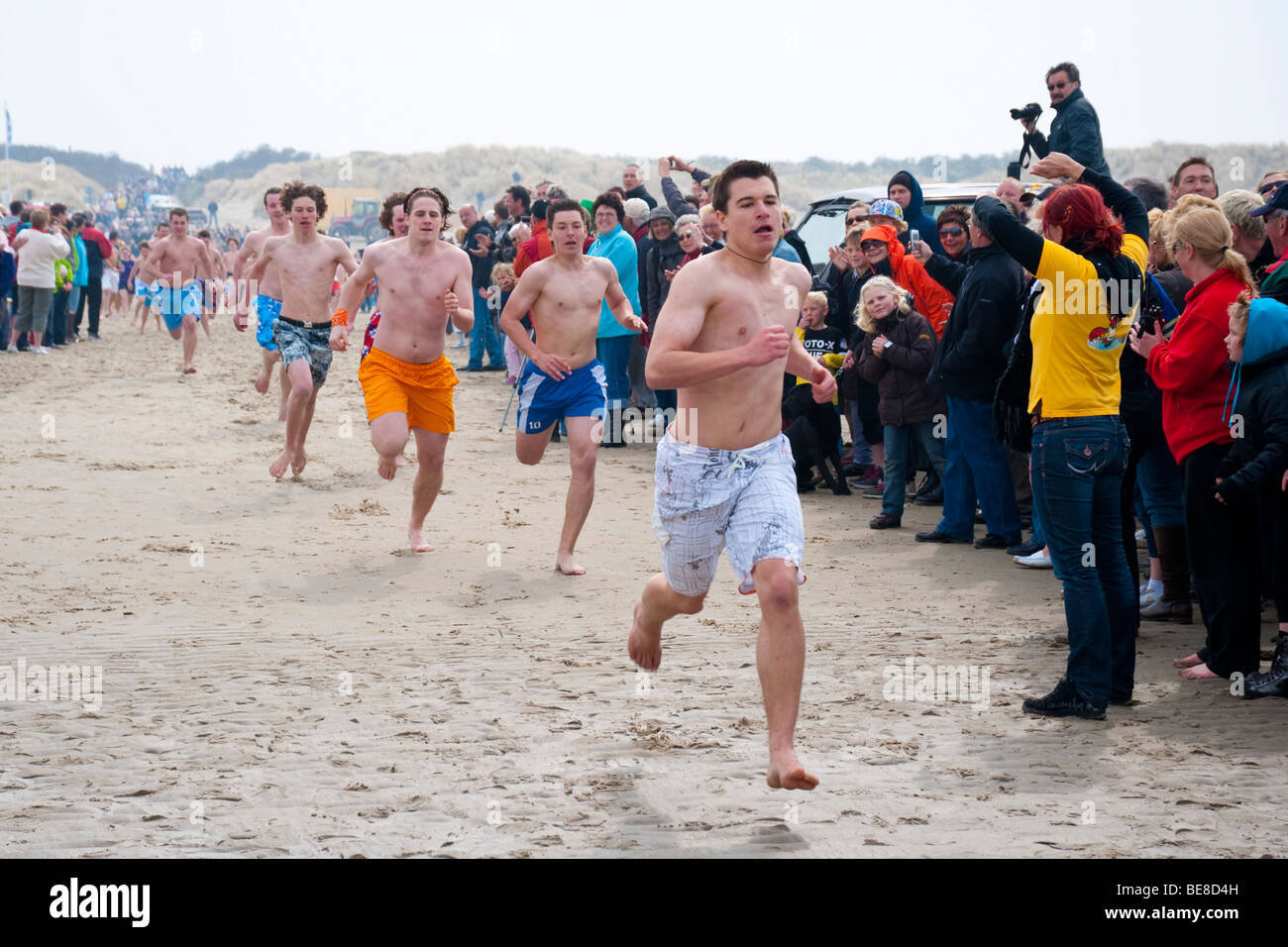 Vacationists in swimwear run down the beach towards the North Sea at ...