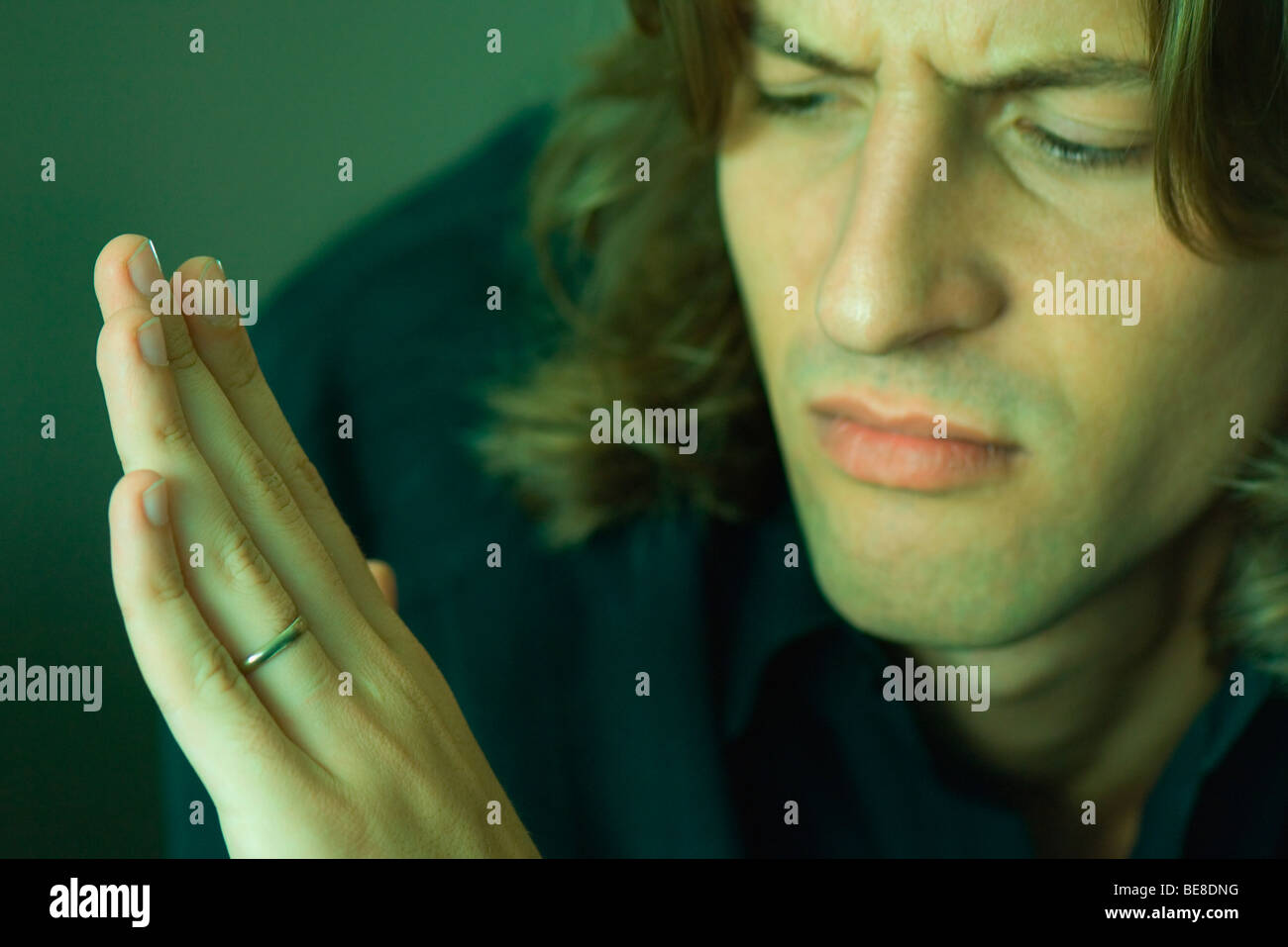 Man furrowing brow looking at own wedding ring Stock Photo - Alamy