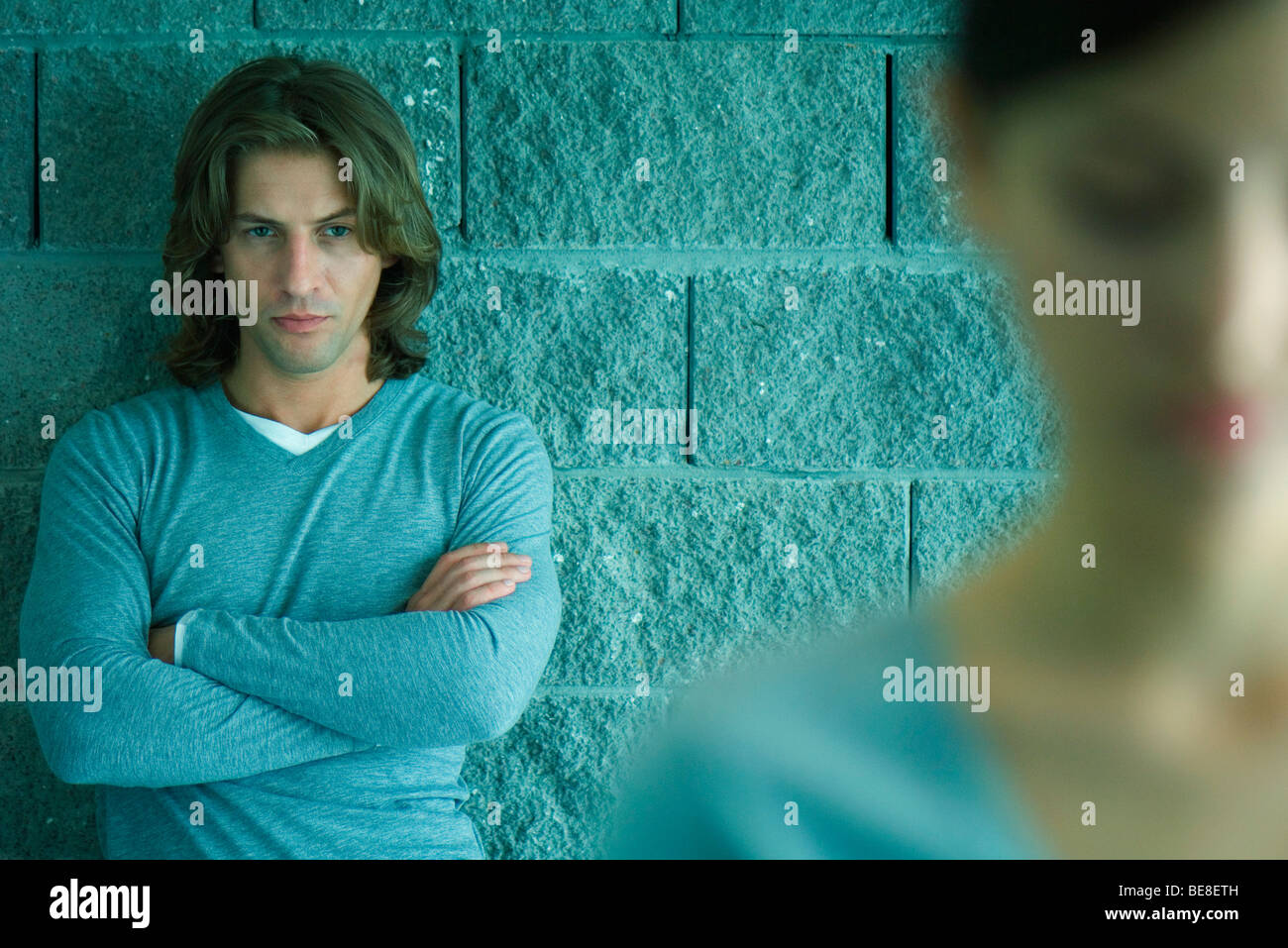 Man with folded arms and sullen expression looking at woman in ...
